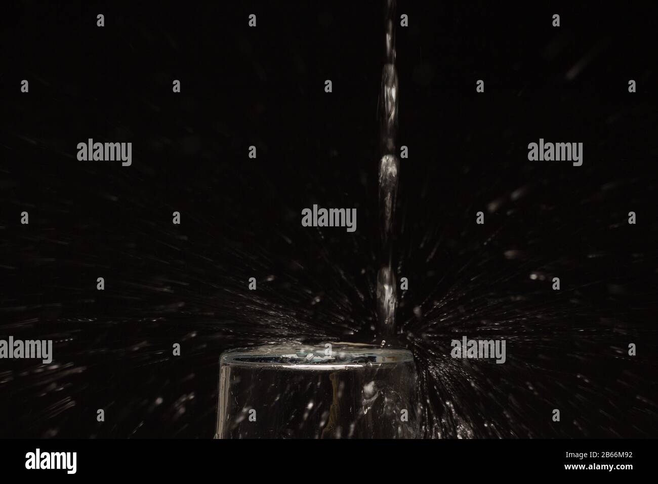 Water jet falling into a glass and generating a splash of water ...