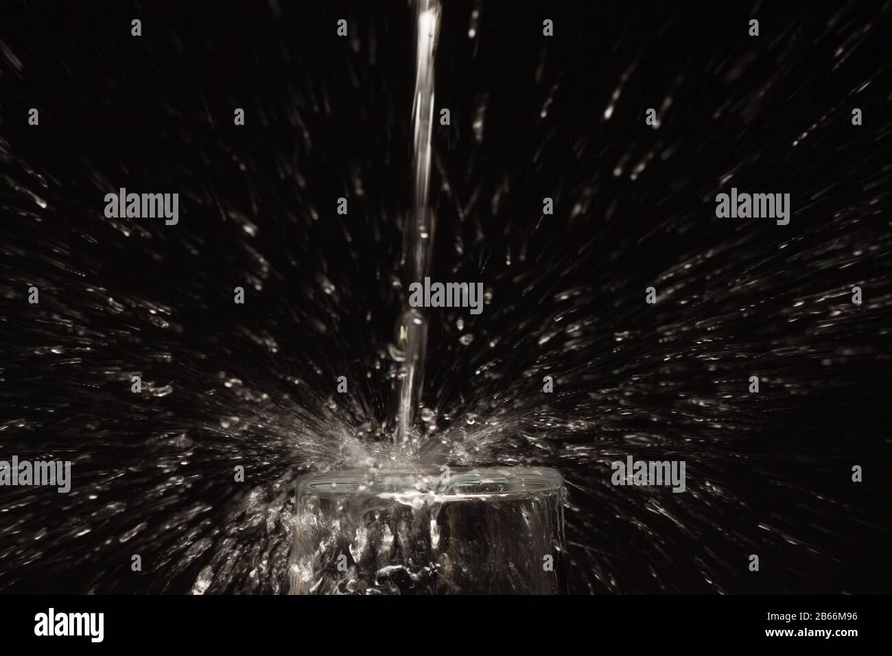 Water jet falling into a glass and generating a splash of water ...