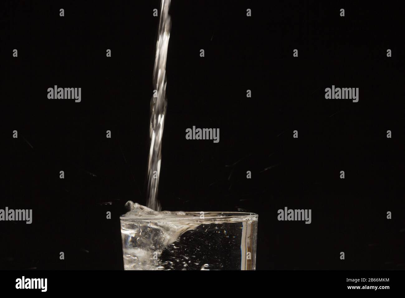 Water jet falling into a glass and generating a splash of water ...