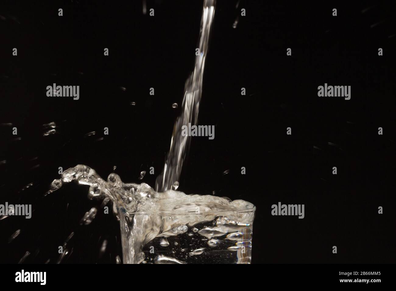 Water jet falling into a glass and generating a splash of water ...