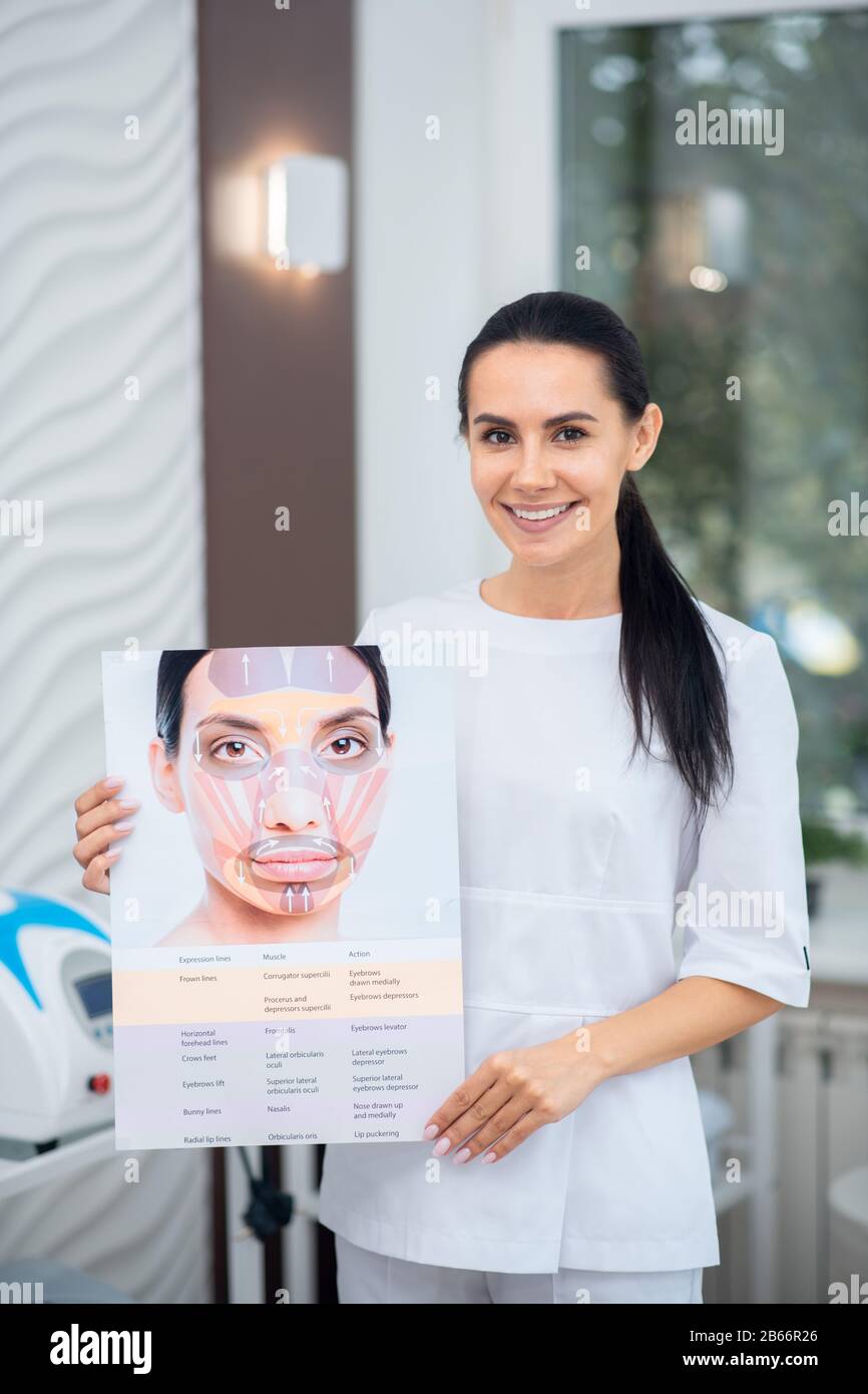 Smiling cosmetologist holding paper with information about face Stock ...