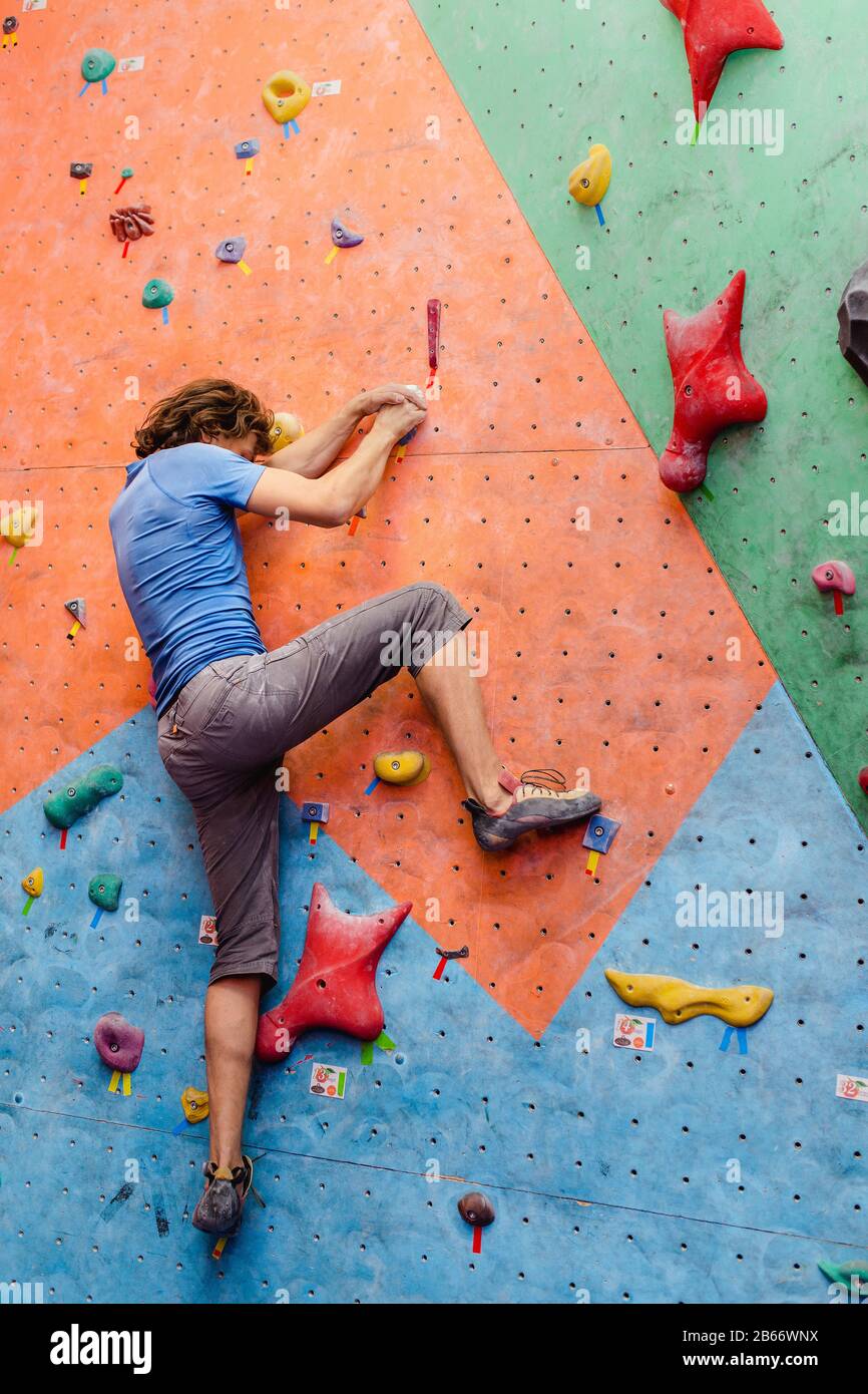 Sport man exercising on artificial climbing wall, modern leisure ...