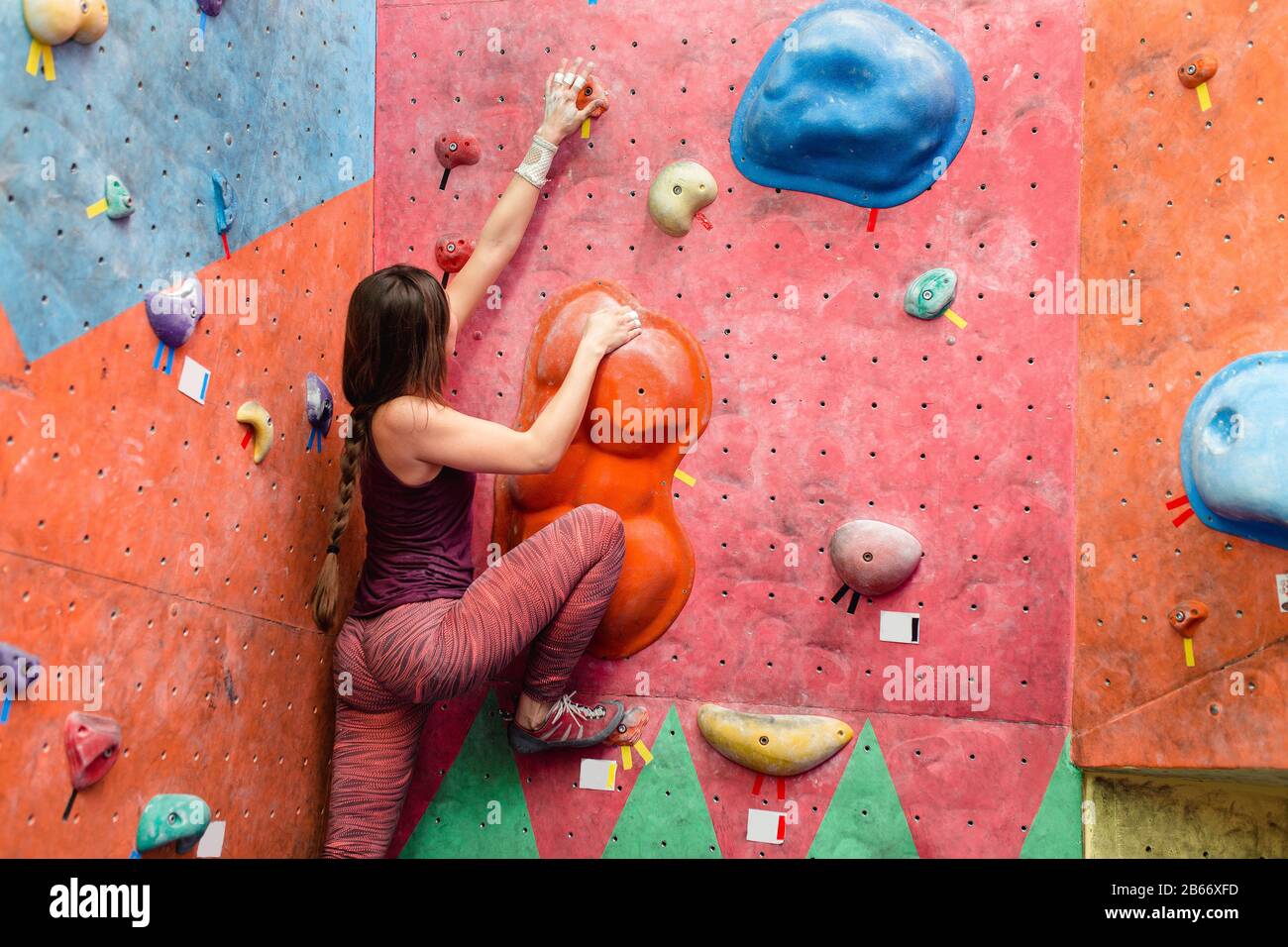 Young strength woman extreme bouldering in a modern rock climbing gym ...
