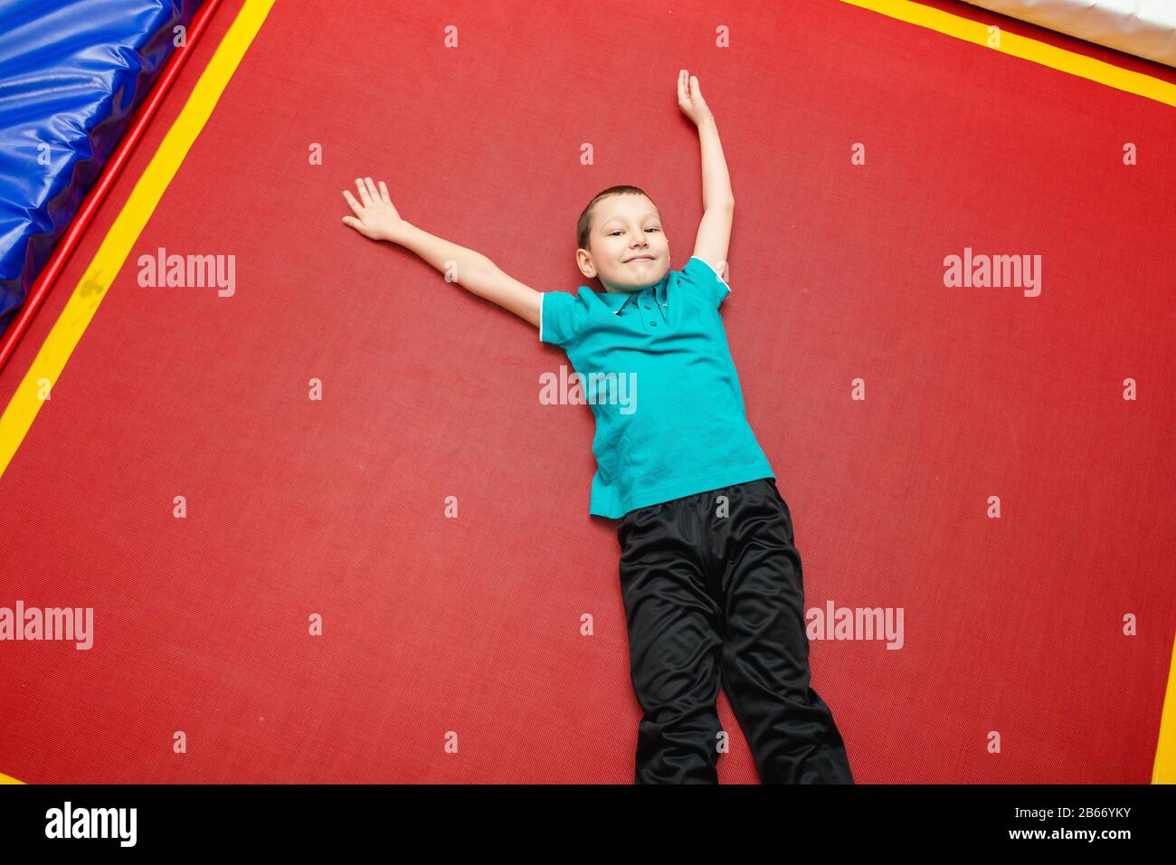 Child boy jumping and lying resting on trampoline, high angle view ...