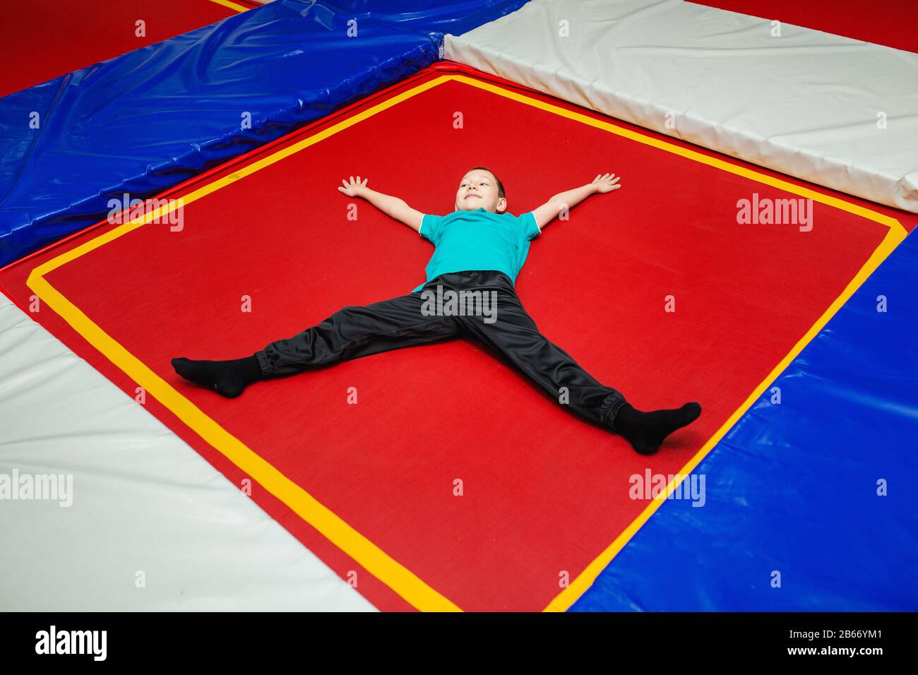 Child boy jumping and lying resting on trampoline, high angle view ...