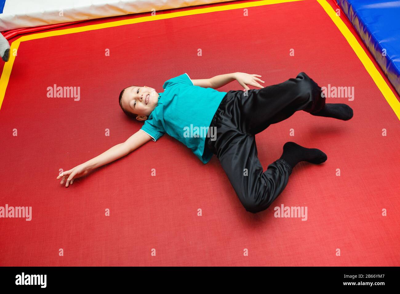Child boy jumping and lying resting on trampoline, high angle view ...