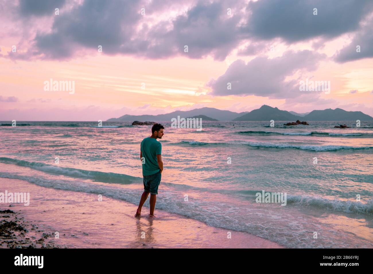La Digue Seychelles,young man in casual clothes on the beach at Anse ...