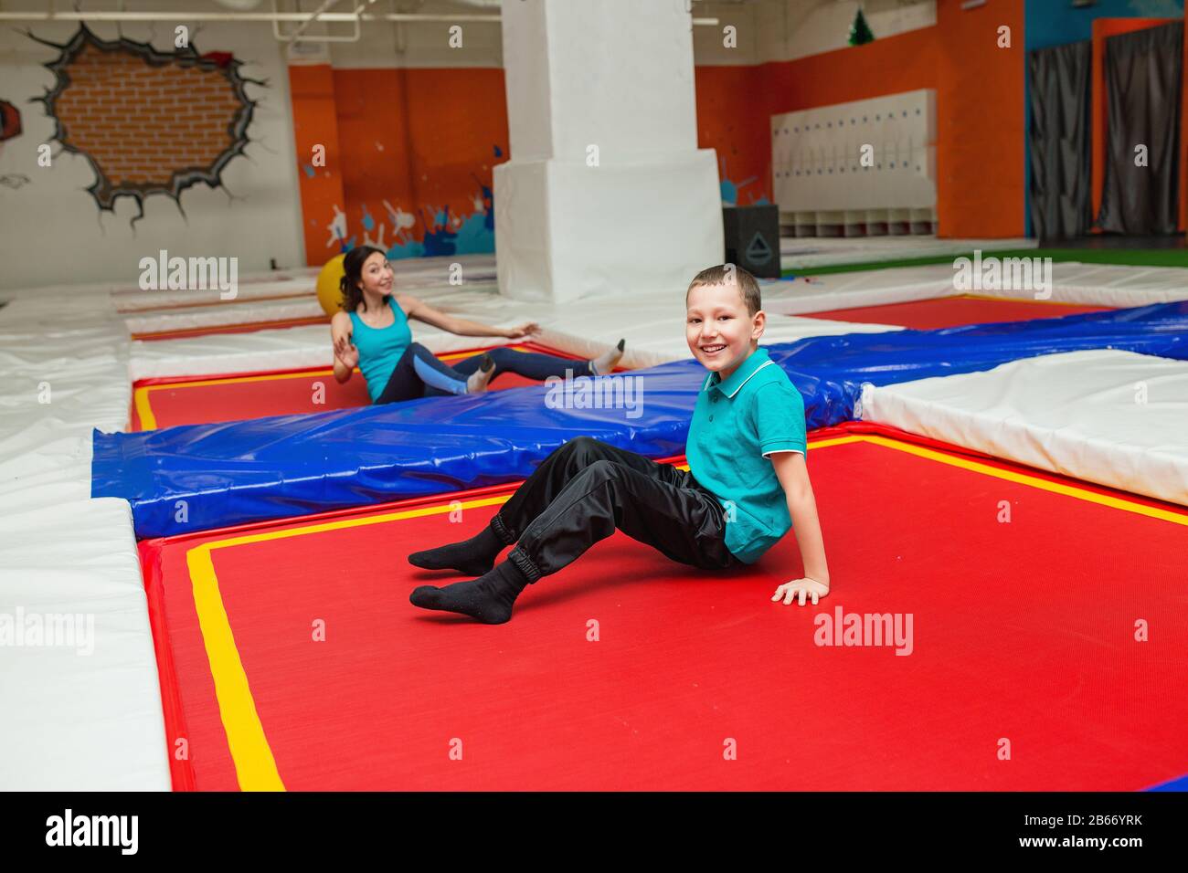 Happy child boy in colorful costume relaxing on trampoline in sport ...