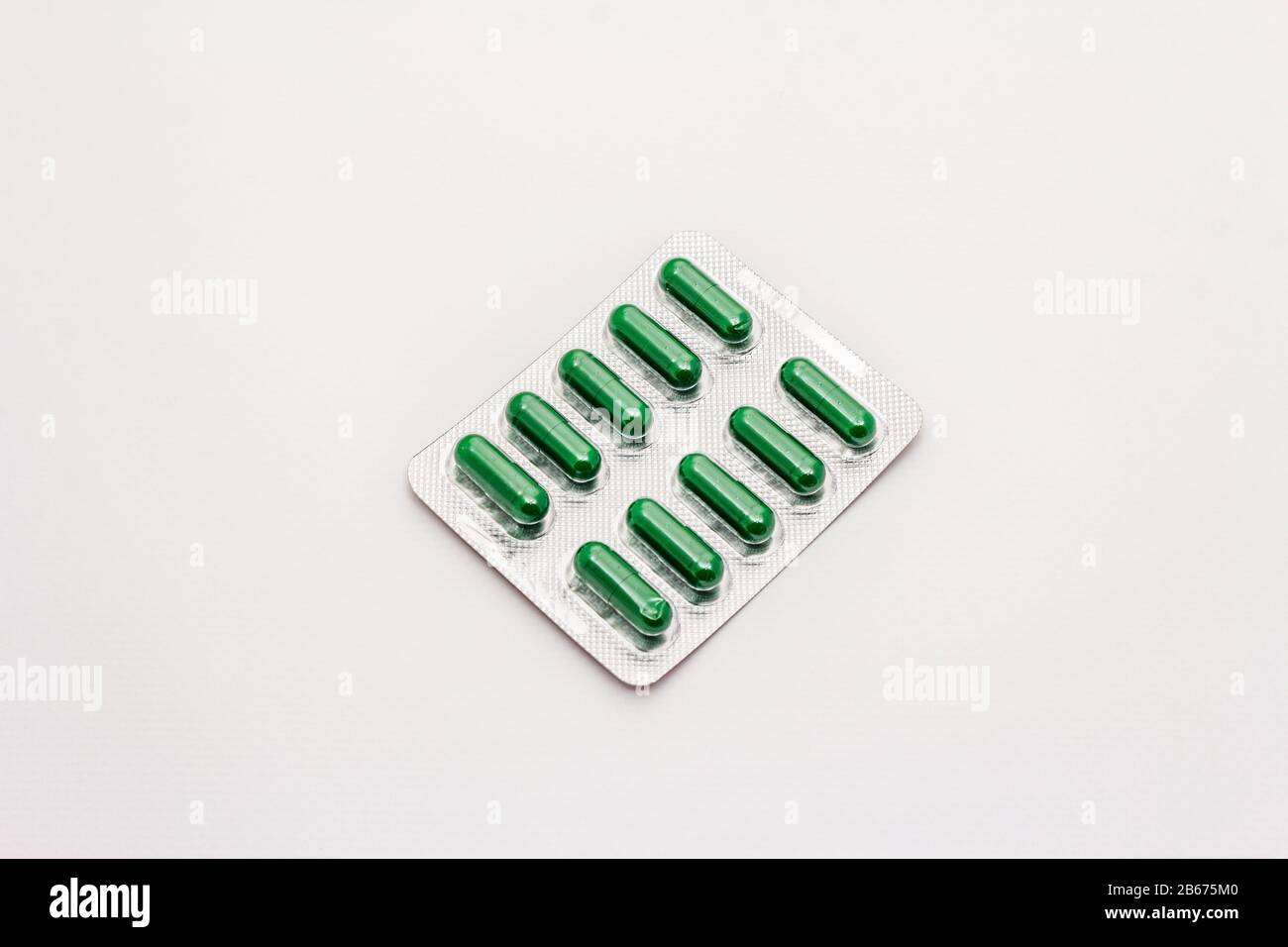 Pharmaceutical tablets, green capsules in blister pack isolated on ...