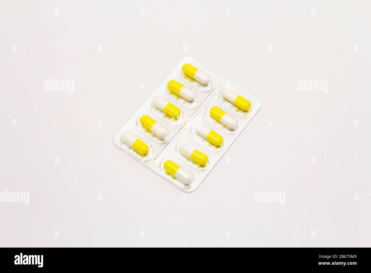 Pharmaceutical tablets, yellow white capsules in blister pack isolated ...