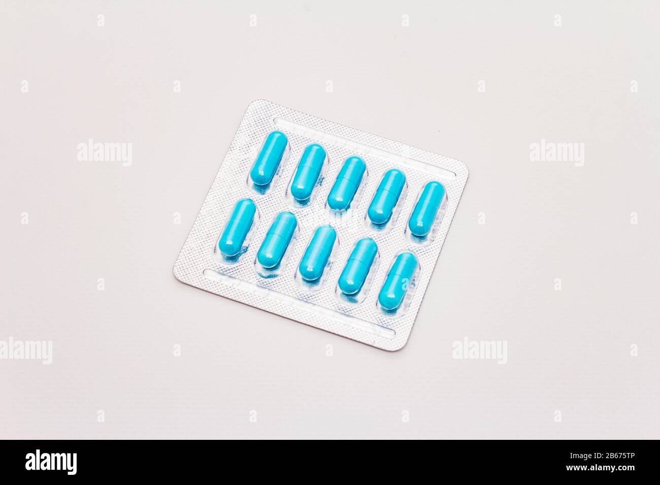 Pharmaceutical tablets, blue capsules in blister pack isolated on white ...