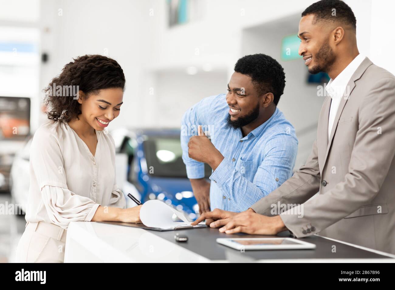 Couple Signing Papers With Car Dealer Buying Auto In Dealership Stock ...