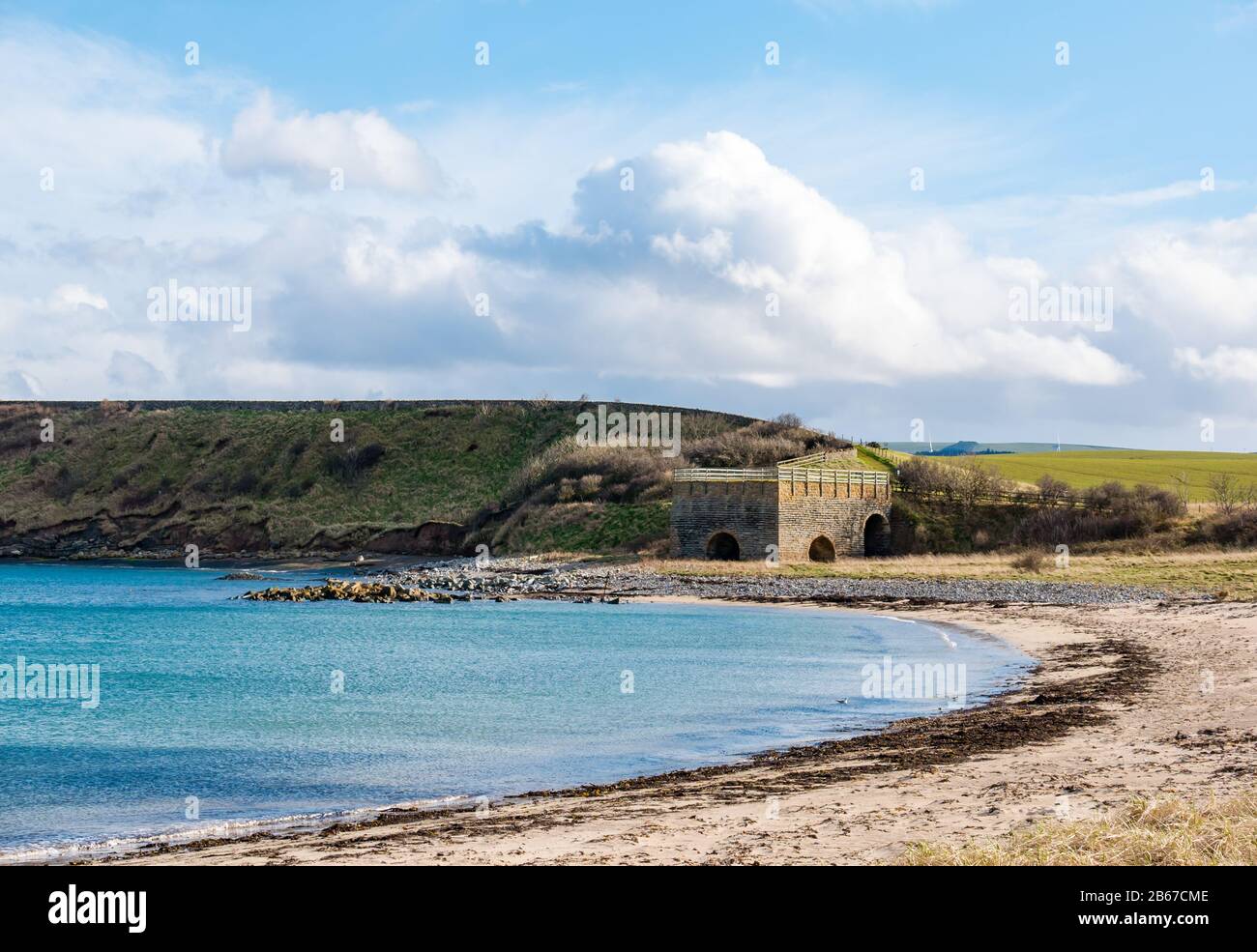 Old stone lime kiln on beach in curved bay in sunshine, Skateraw, East ...