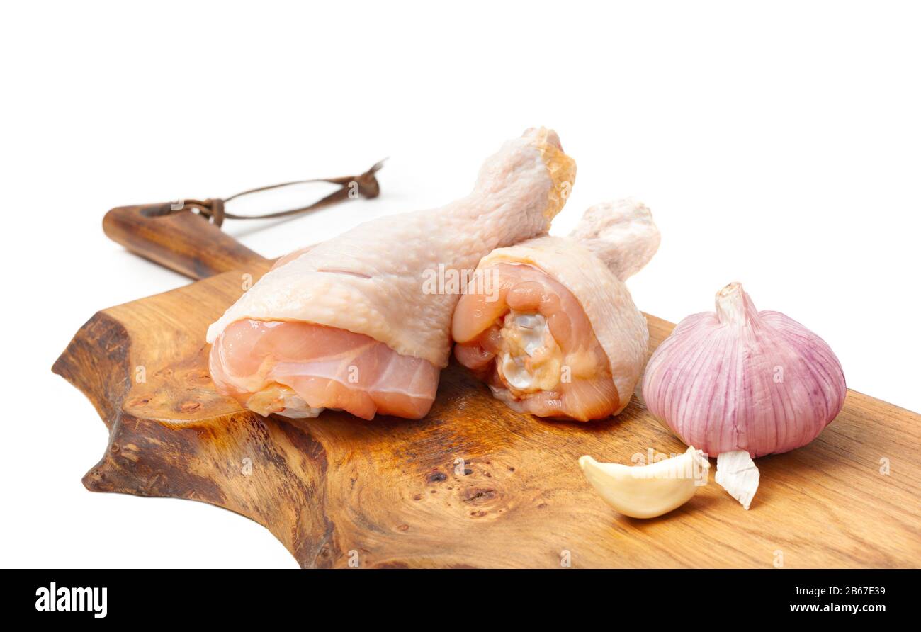 Raw uncooked chicken legs with garlic, drumsticks on wooden board ...