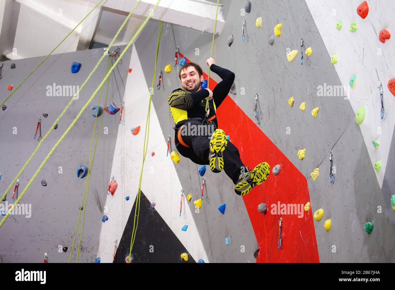 Young man climbing indoor wall and reaching the top Stock Photo - Alamy
