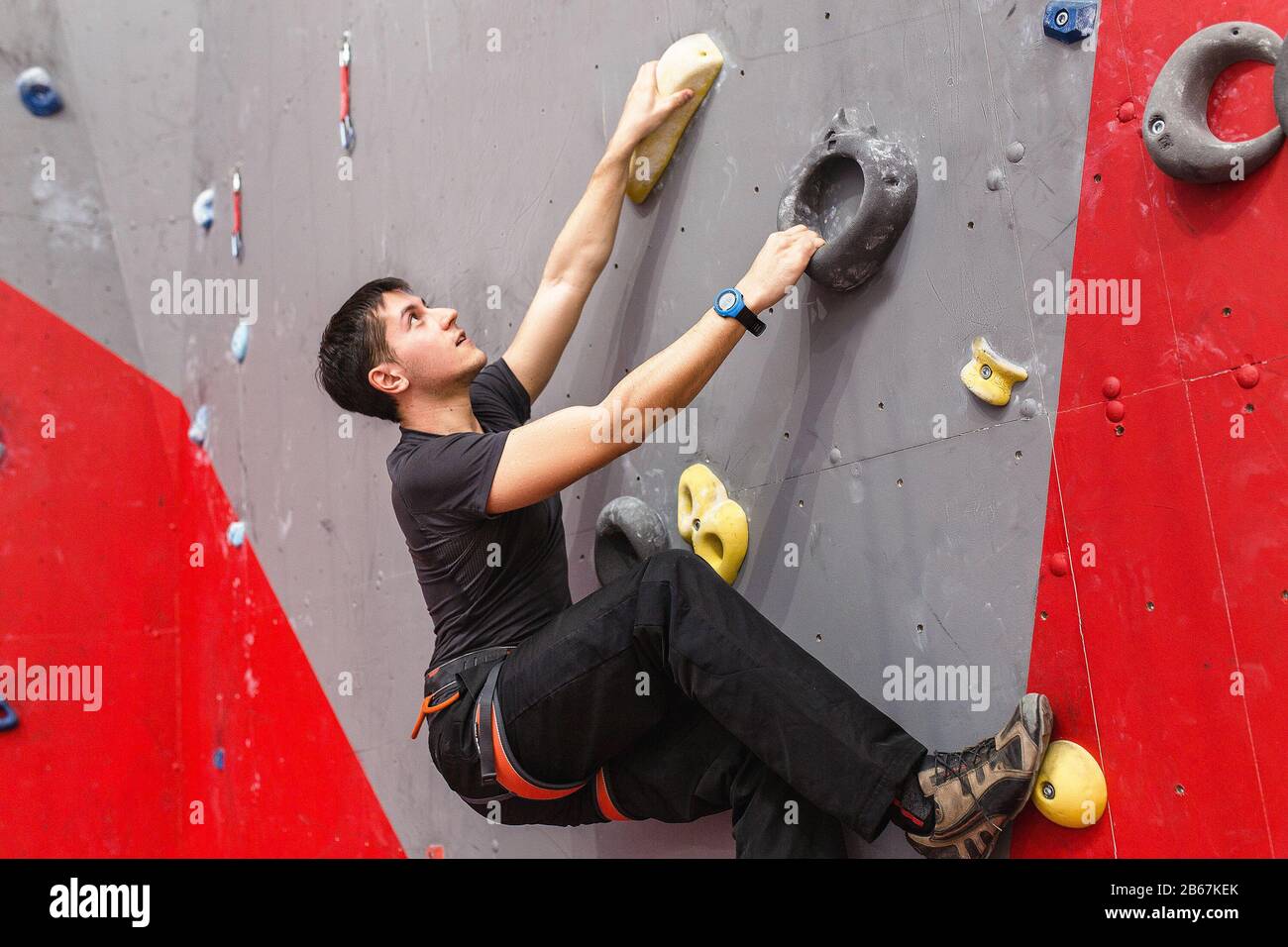 Man climbing up rock wall at the gym indoors Stock Photo - Alamy