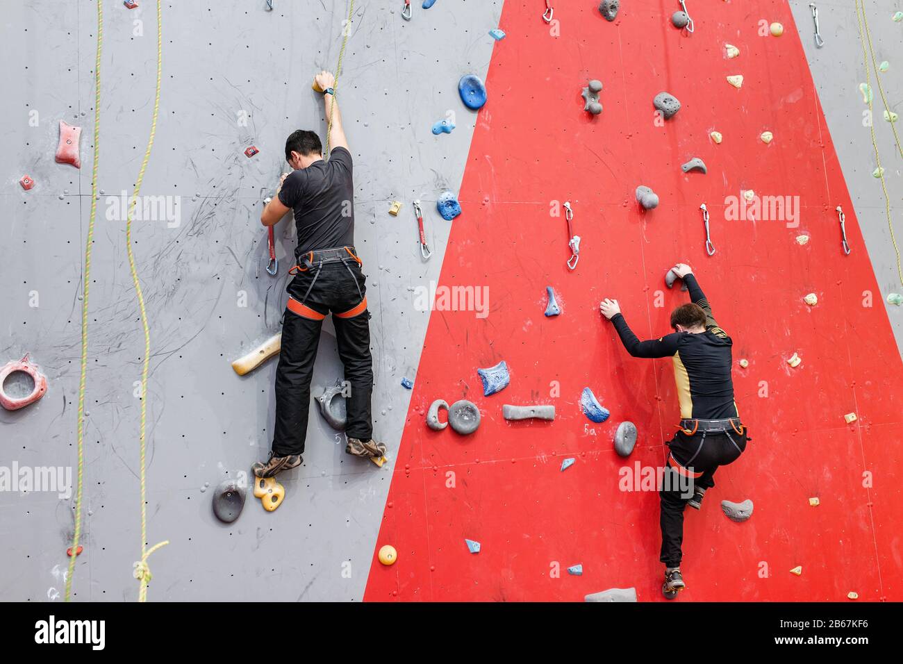 Two climbers compete in a friendly match in the climbing gym indoors ...