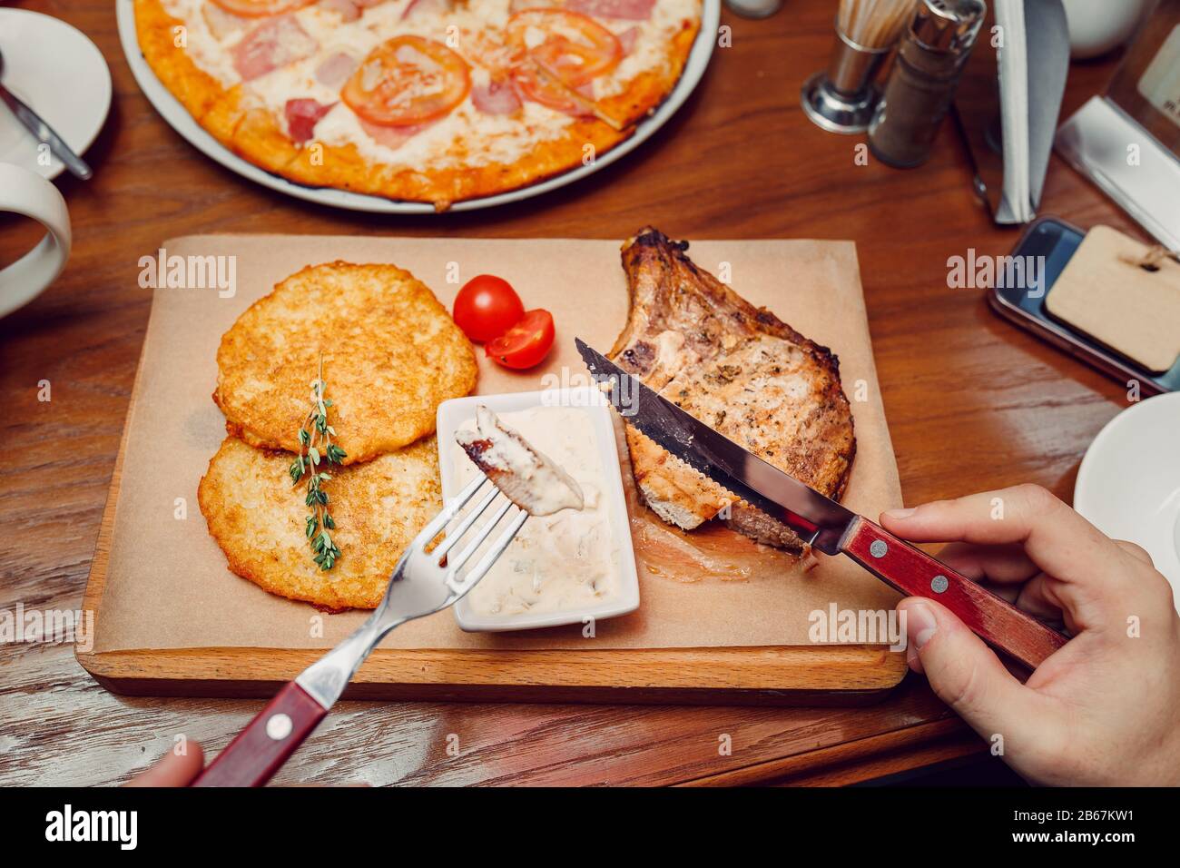Woman eating with a fork and a knife pork steak in a restaurant Stock ...