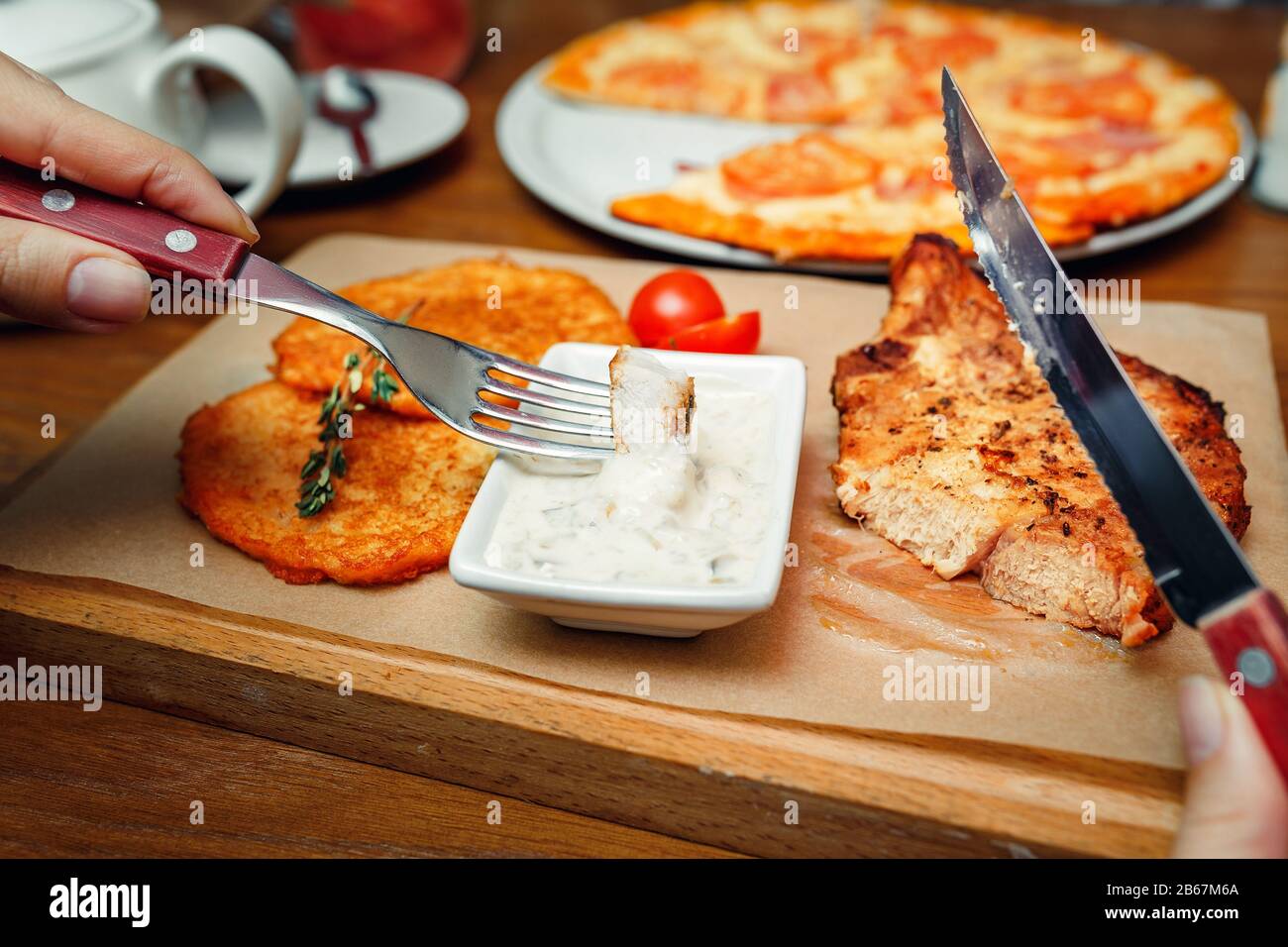 Woman eating with a fork and a knife pork steak in a restaurant Stock ...