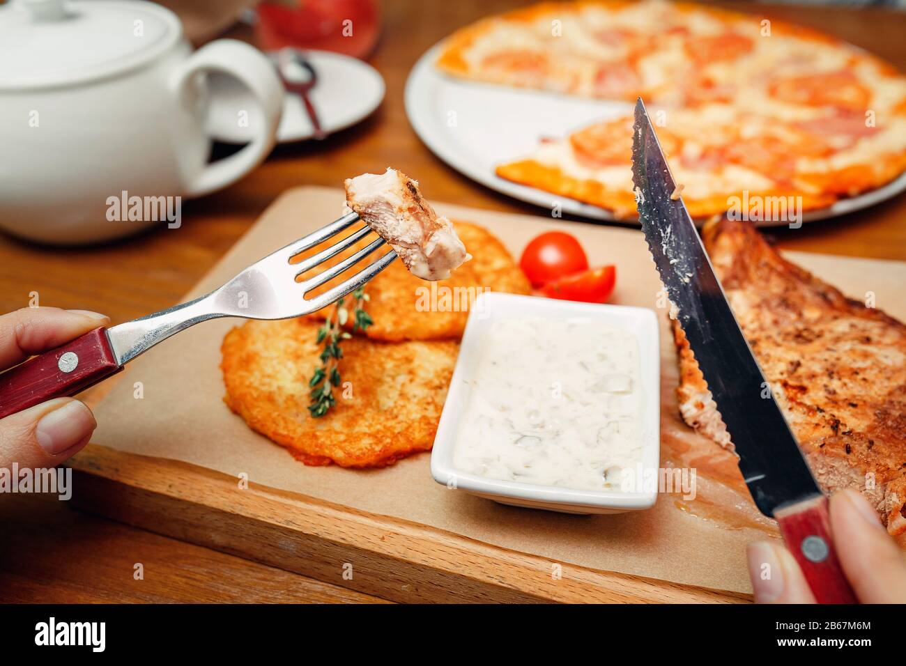 Woman eating with a fork and a knife pork steak in a restaurant Stock ...