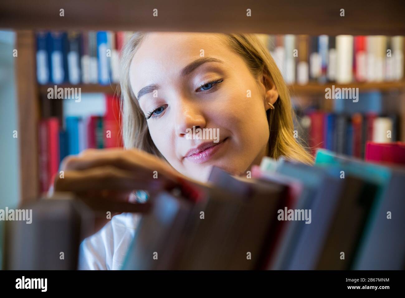 Young girl standing in traditional old library at bookshelves, looking ...