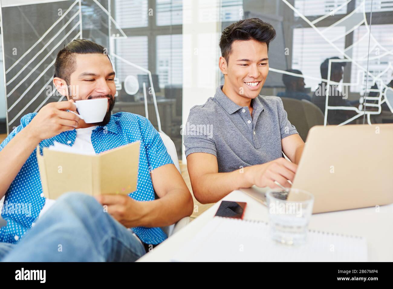 Two start-up programmers working on laptop computers in the office ...
