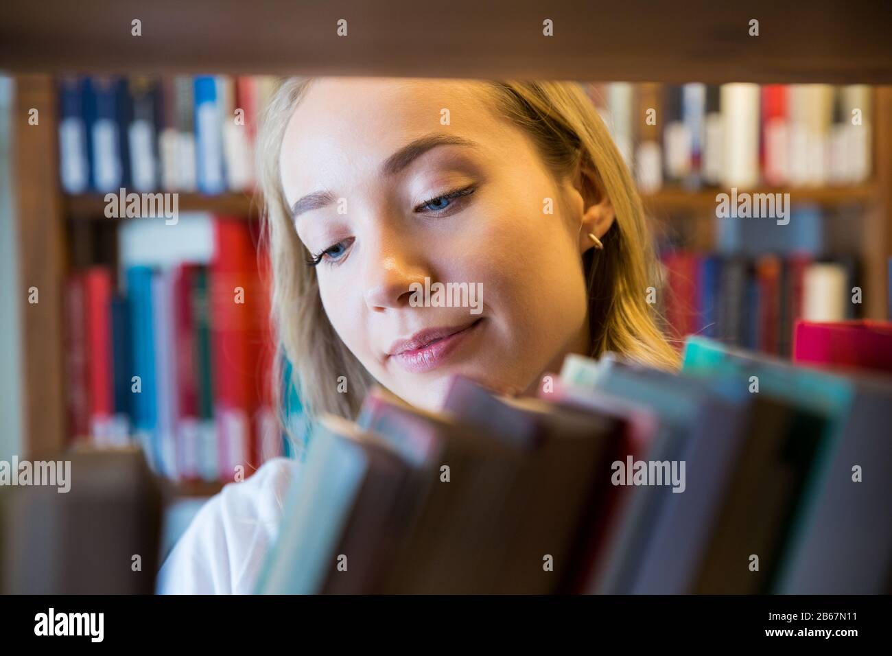 Young girl standing in traditional old library at bookshelves, looking ...