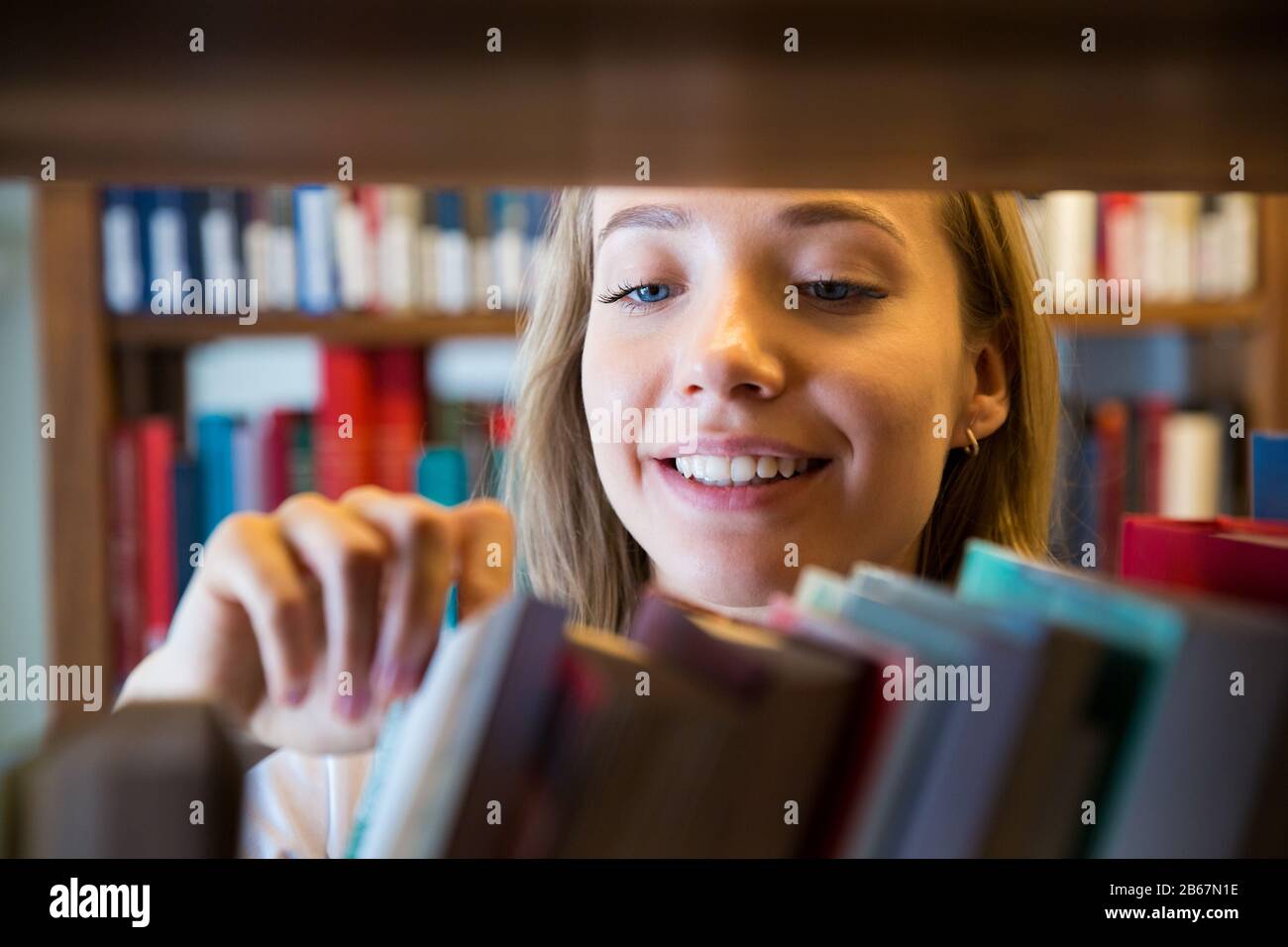 Young girl standing in traditional old library at bookshelves, looking ...