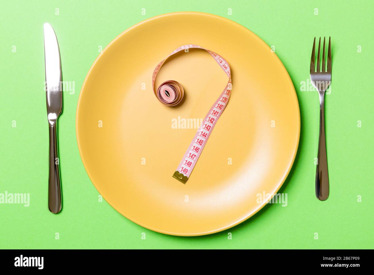 Question mark made of measuring tape on round plate on green background ...