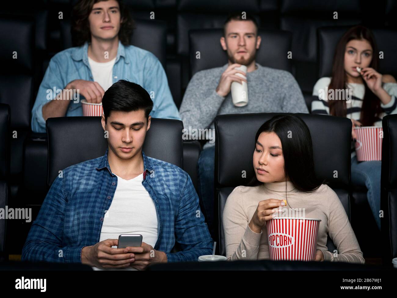 Premiere night. Millennial man checking mobile phone while watching ...