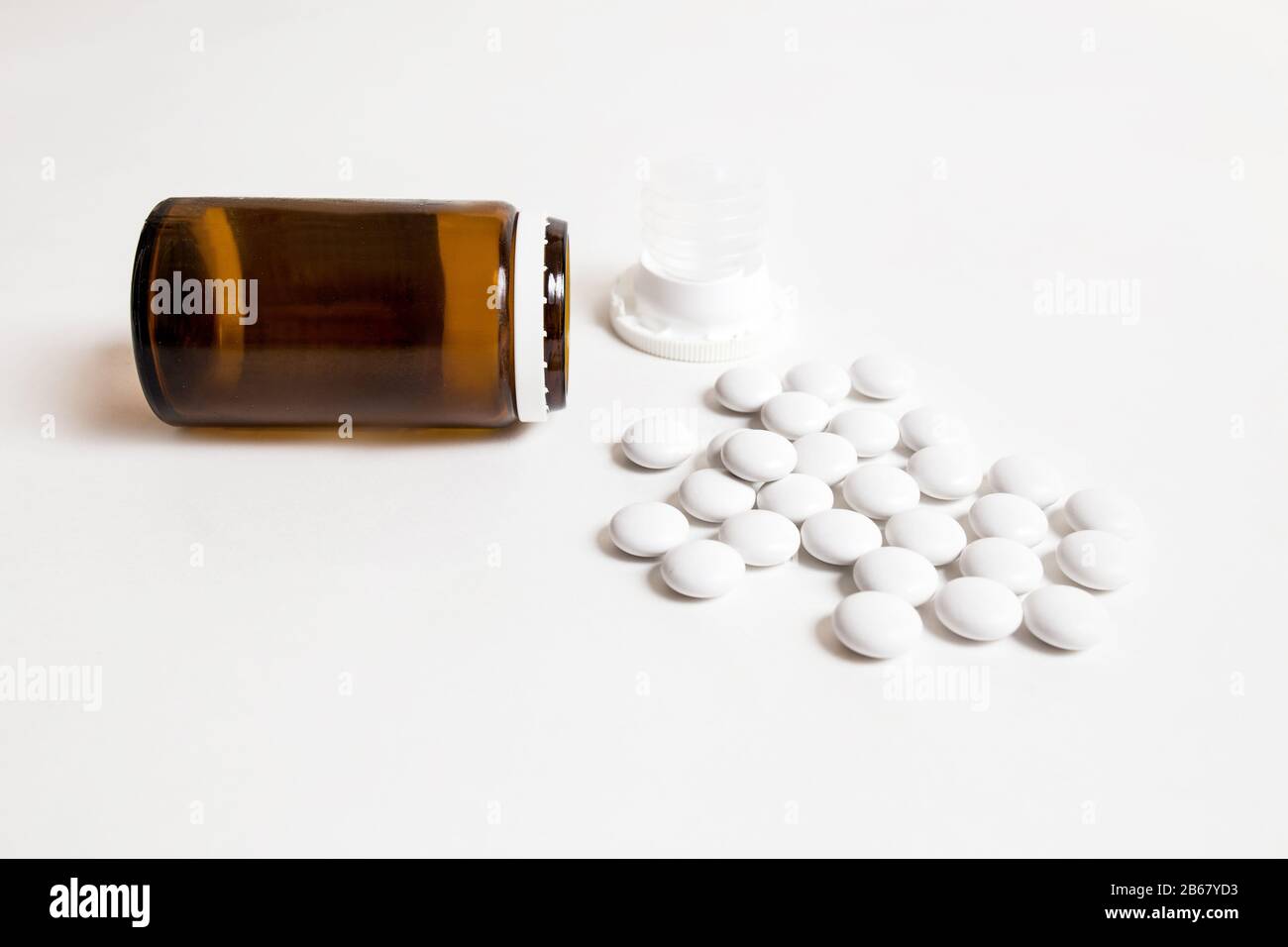 Vial with scattered medication tablets on white Stock Photo - Alamy