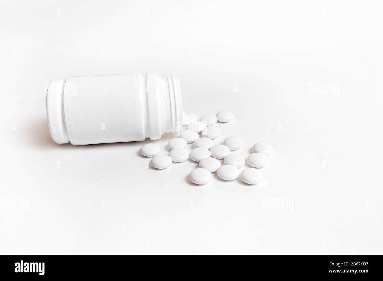 Vial with scattered medication tablets on white Stock Photo - Alamy