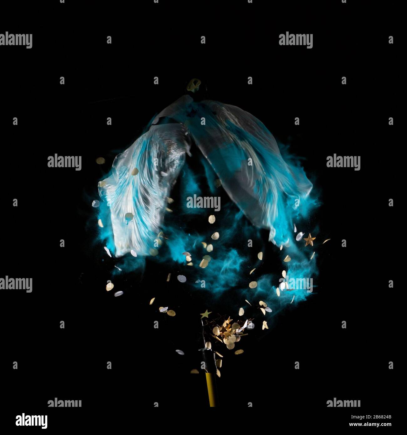 Bursting balloon full of coloured powder and glitter on a black ...