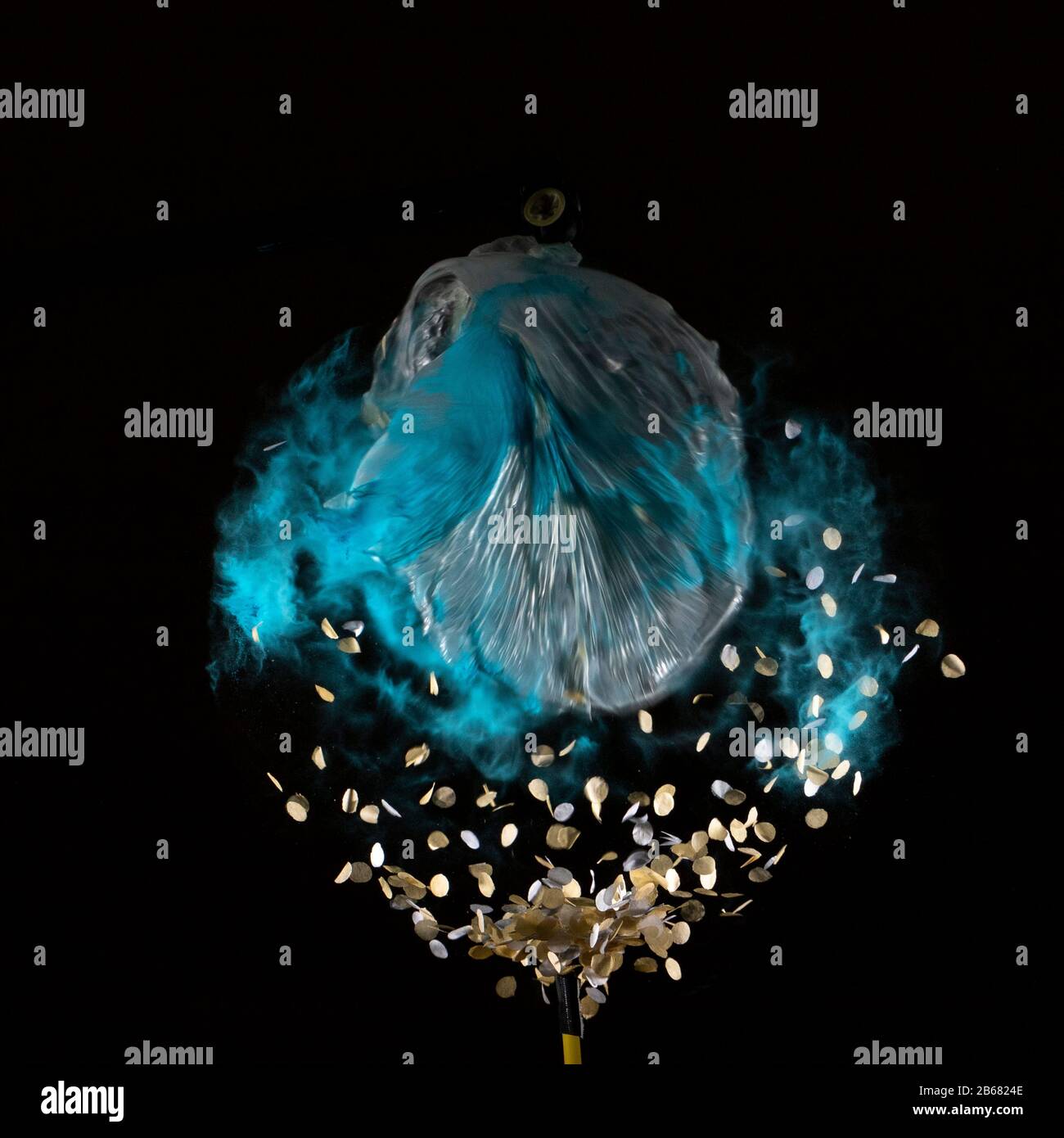 Bursting balloon full of coloured powder and glitter on a black ...