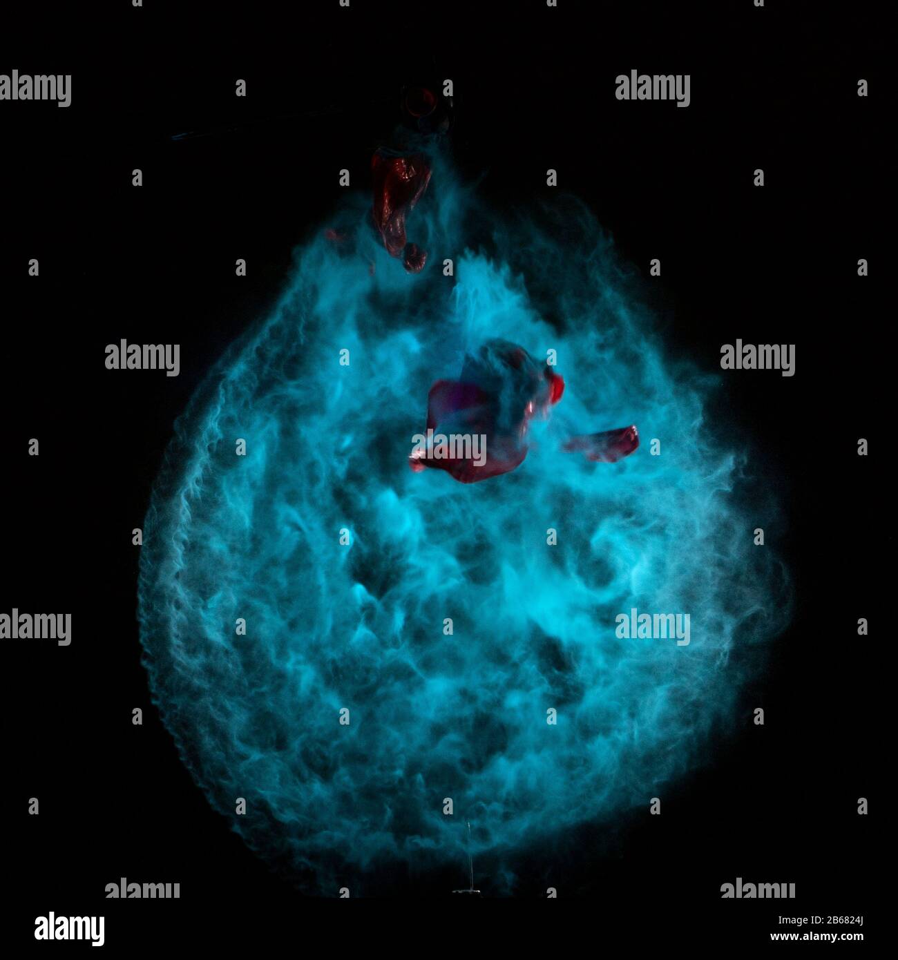 Bursting balloon full of coloured powder and glitter on a black ...