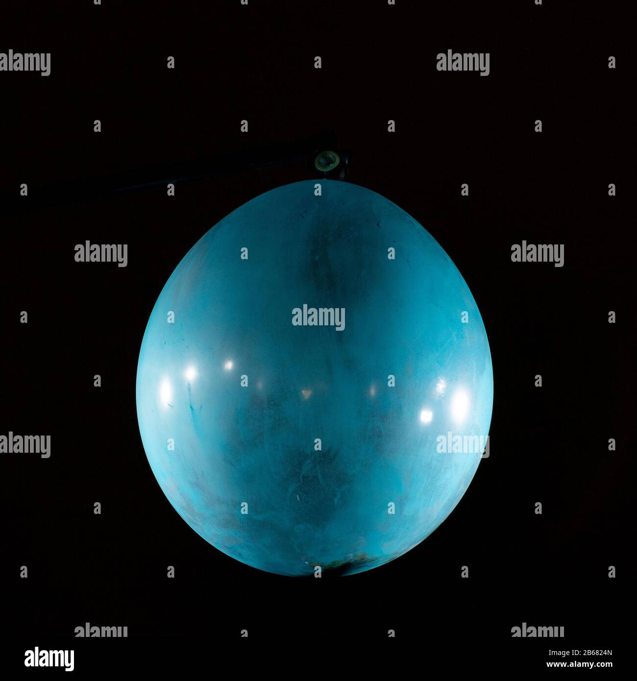 Bursting balloon full of coloured powder and glitter on a black ...