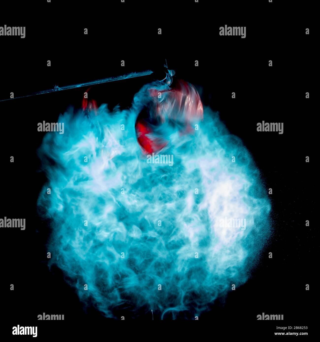 Bursting balloon full of coloured powder and glitter on a black ...