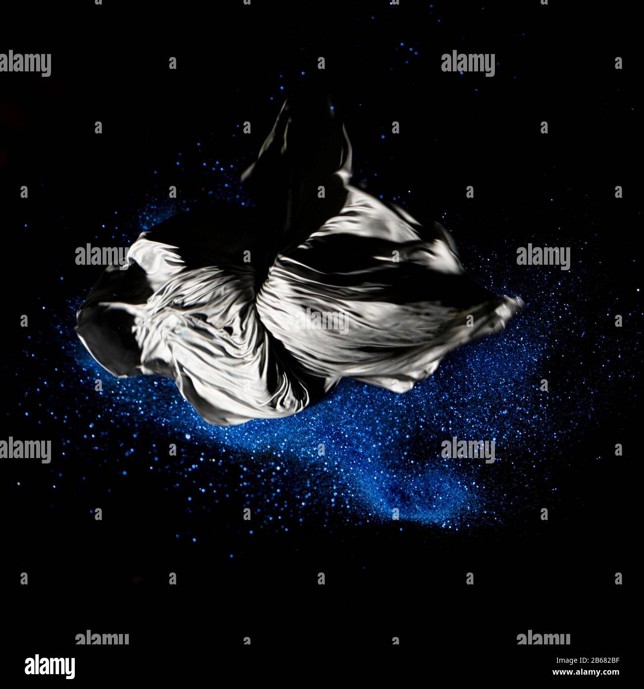 Bursting balloon full of coloured powder and glitter on a black ...