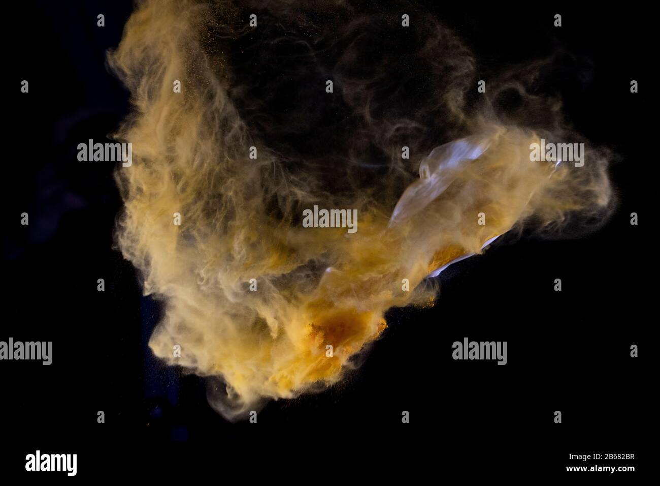 Bursting balloon full of coloured powder and glitter on a black ...