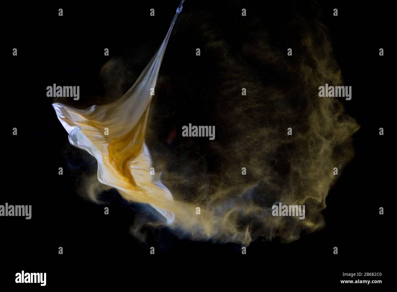 Bursting balloon full of coloured powder and glitter on a black ...