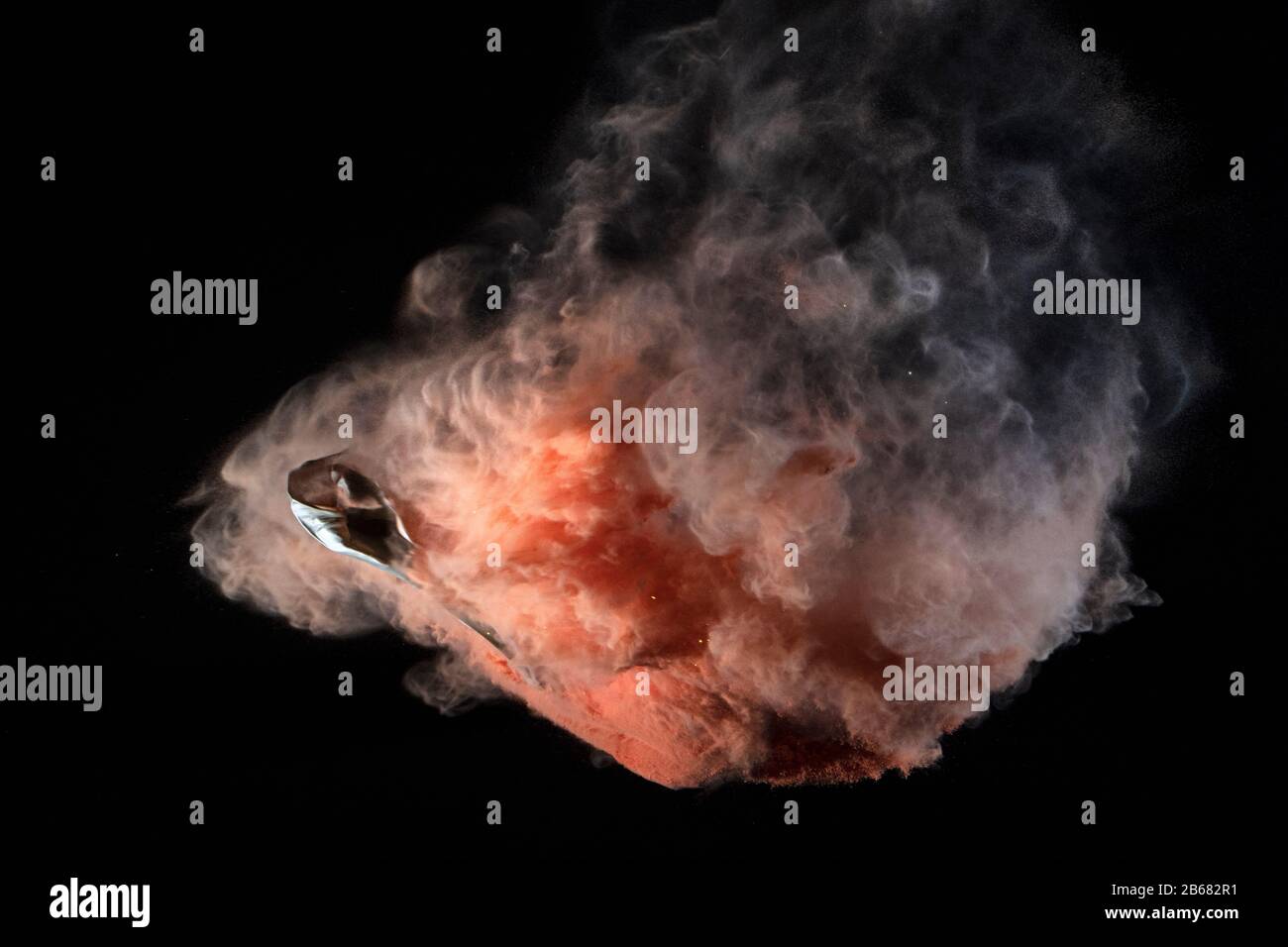 Bursting balloon full of coloured powder and glitter on a black ...