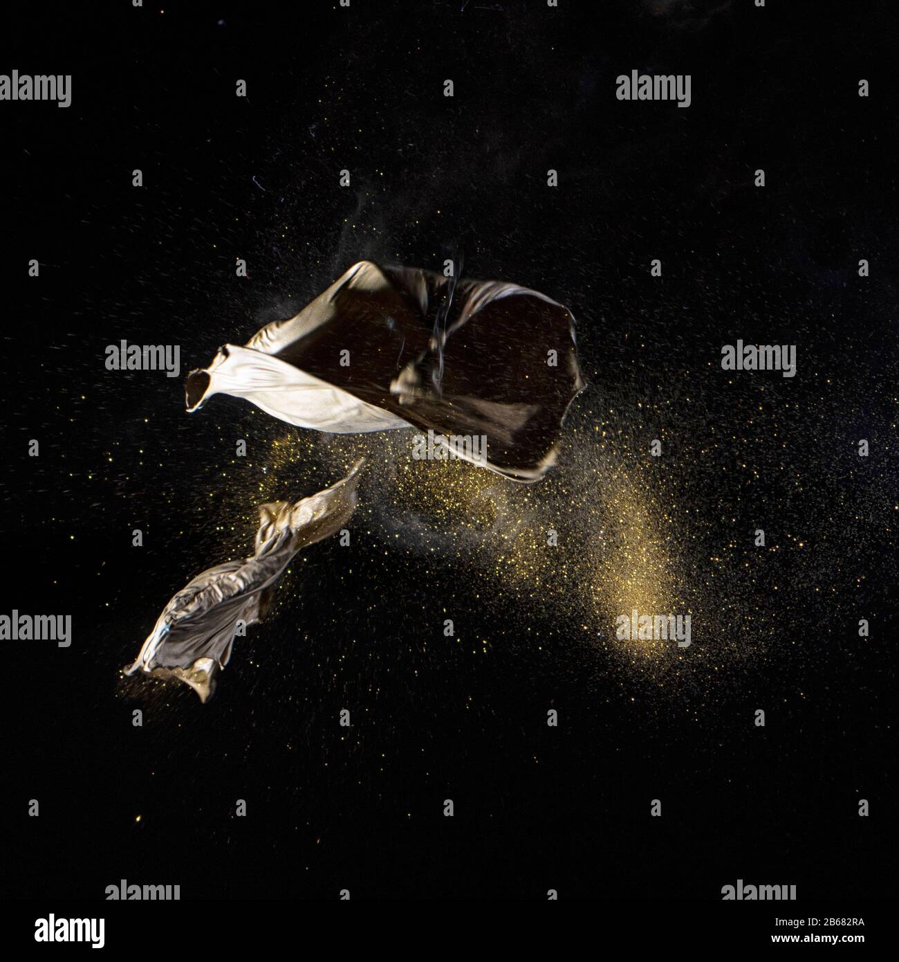 Bursting balloon full of coloured powder and glitter on a black ...