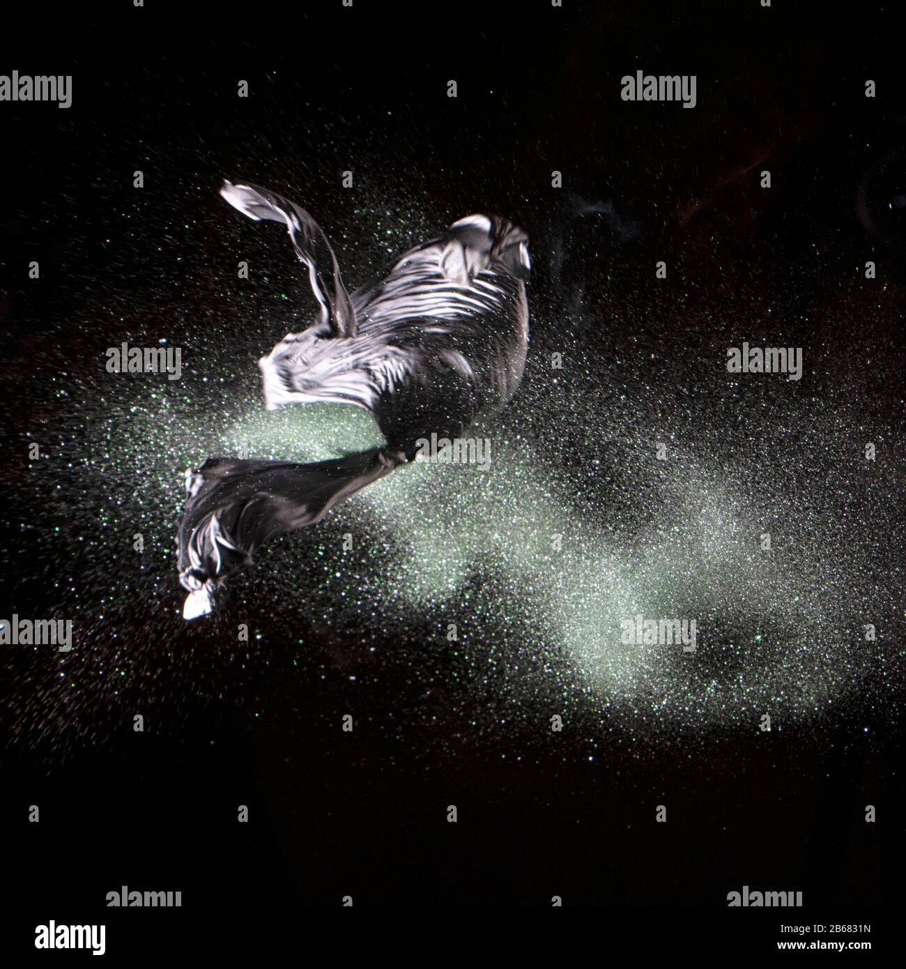 Bursting balloon full of coloured powder and glitter on a black ...