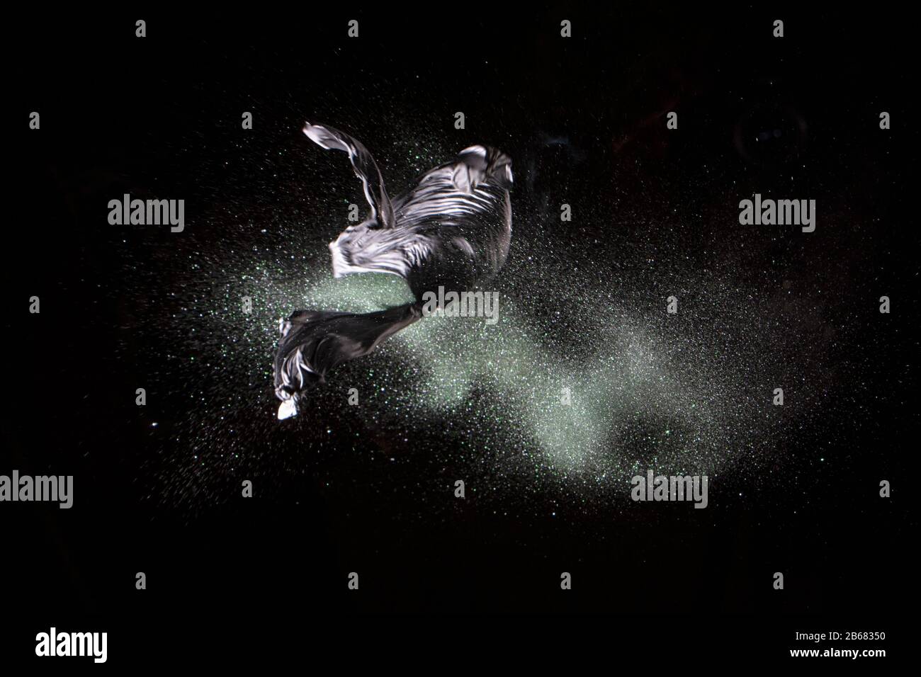 Bursting balloon full of coloured powder and glitter on a black ...