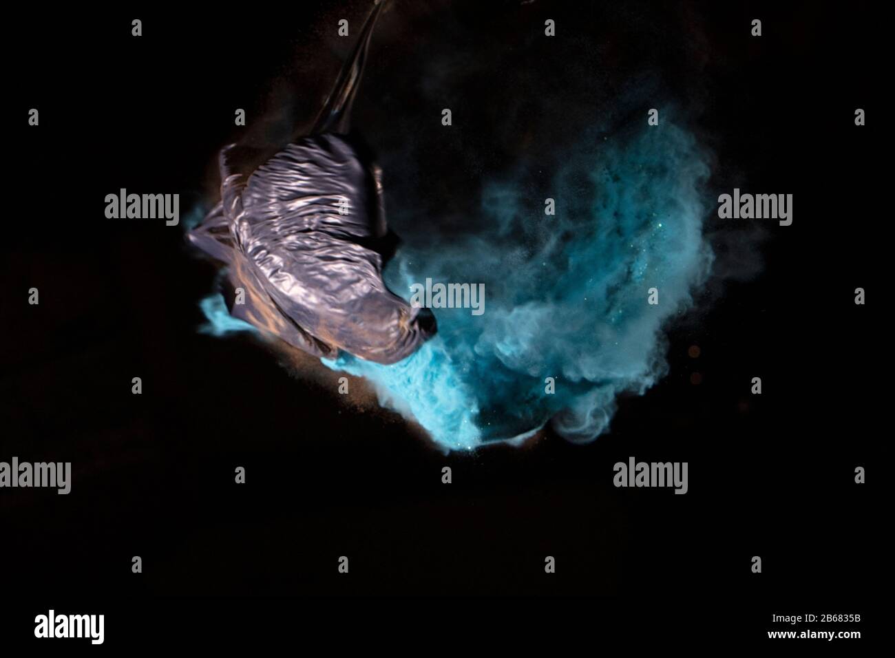 Bursting balloon full of coloured powder and glitter on a black ...