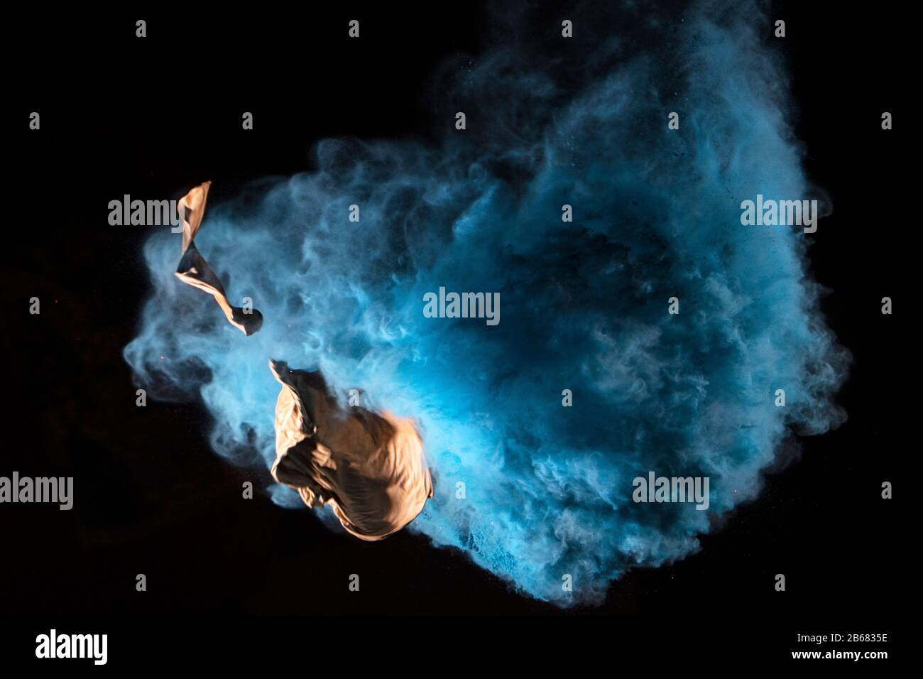 Bursting balloon full of coloured powder and glitter on a black ...