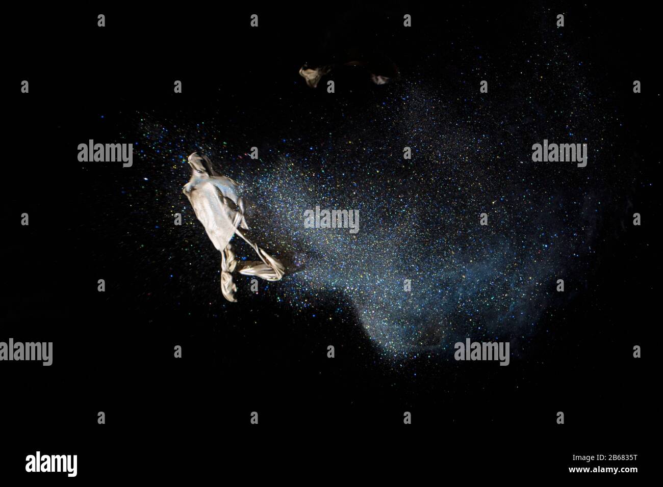 Bursting balloon full of coloured powder and glitter on a black ...