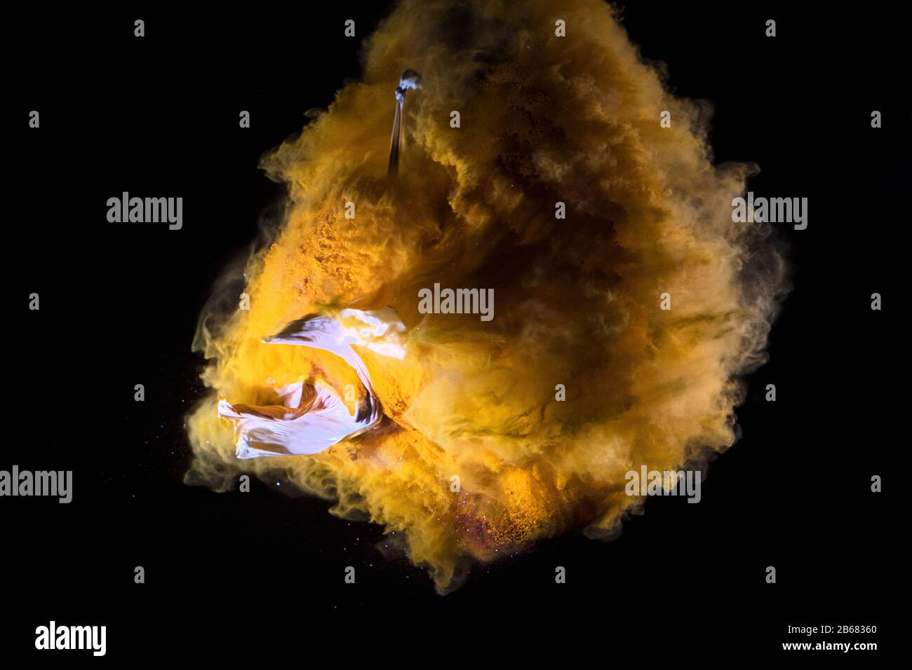 Bursting balloon full of coloured powder and glitter on a black ...