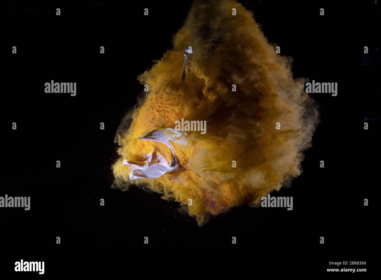 Bursting balloon full of coloured powder and glitter on a black ...