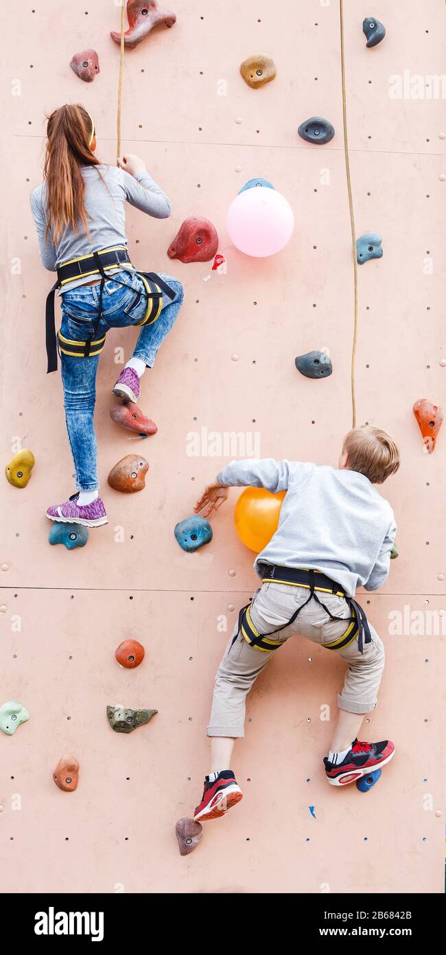 Two children climb the bouldering artificial wall and compete in speed ...